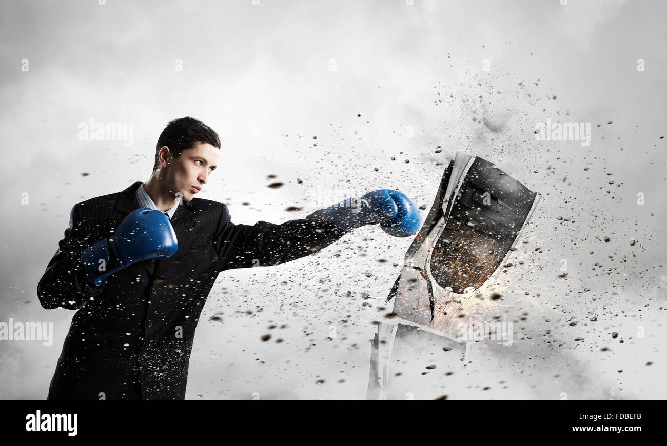 Young businessman in blue boxing gloves breaking computer Stock Photo ...