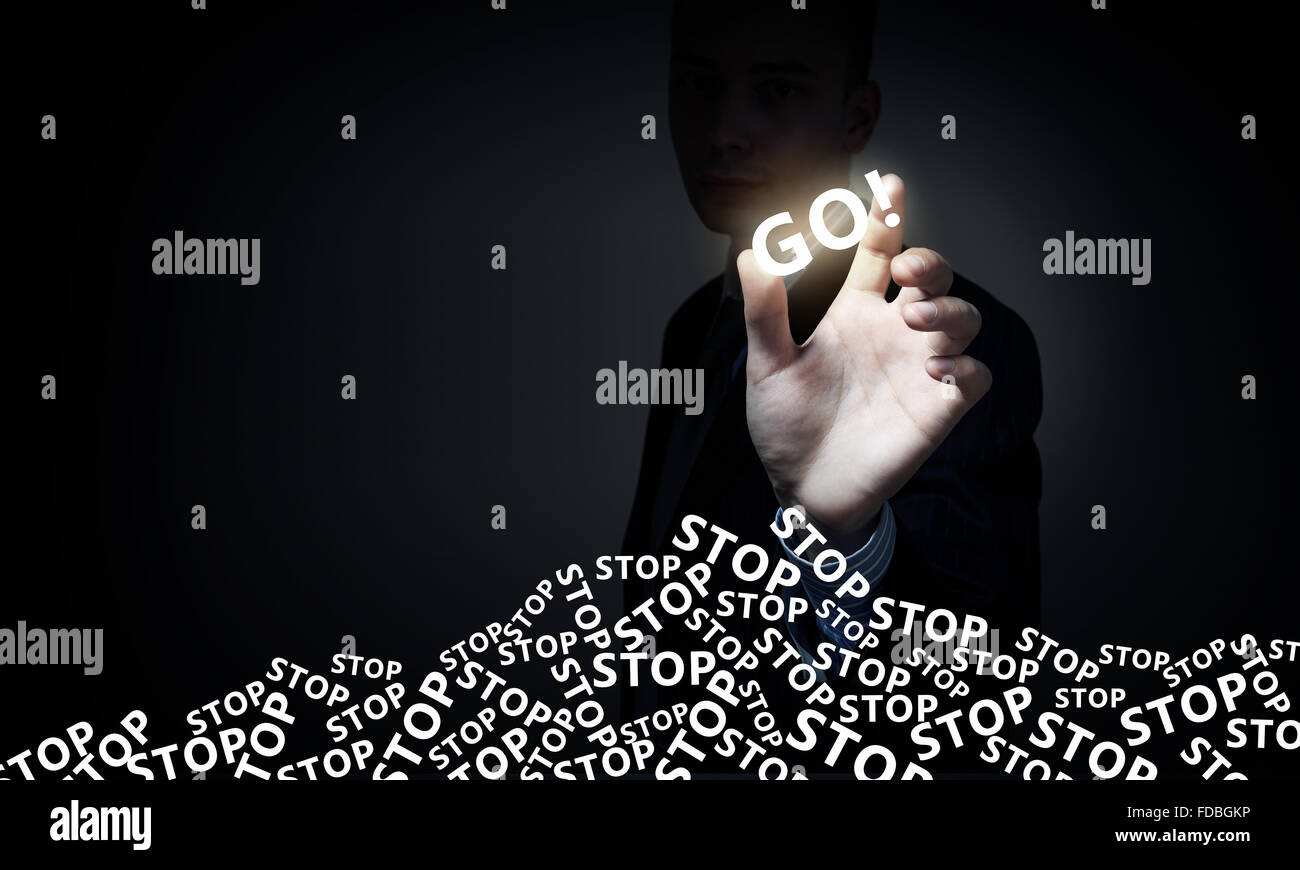 Businessman on dark background taking with fingers word go Stock Photo ...