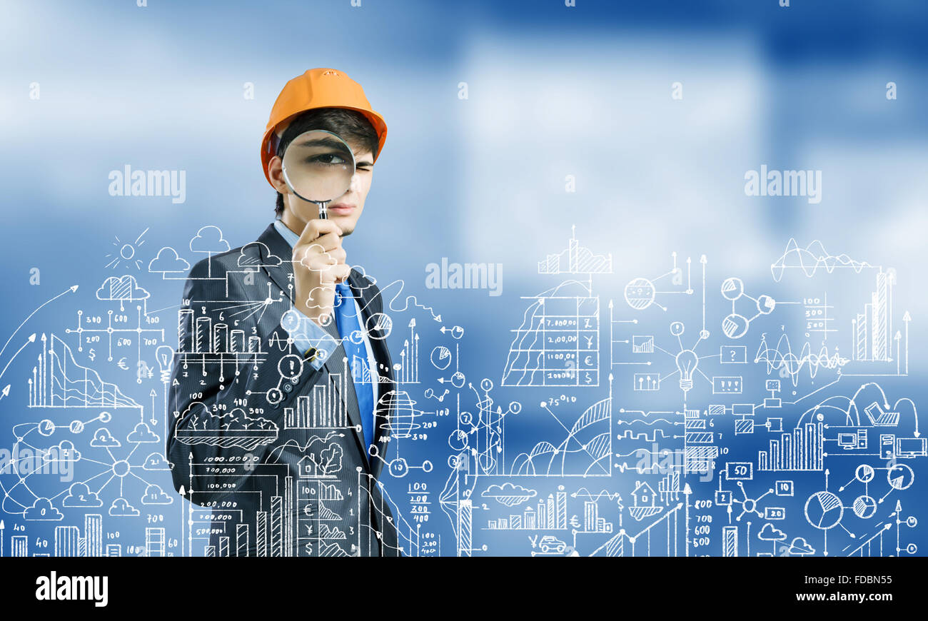 Young man architect against sketch background looking in magnifying ...
