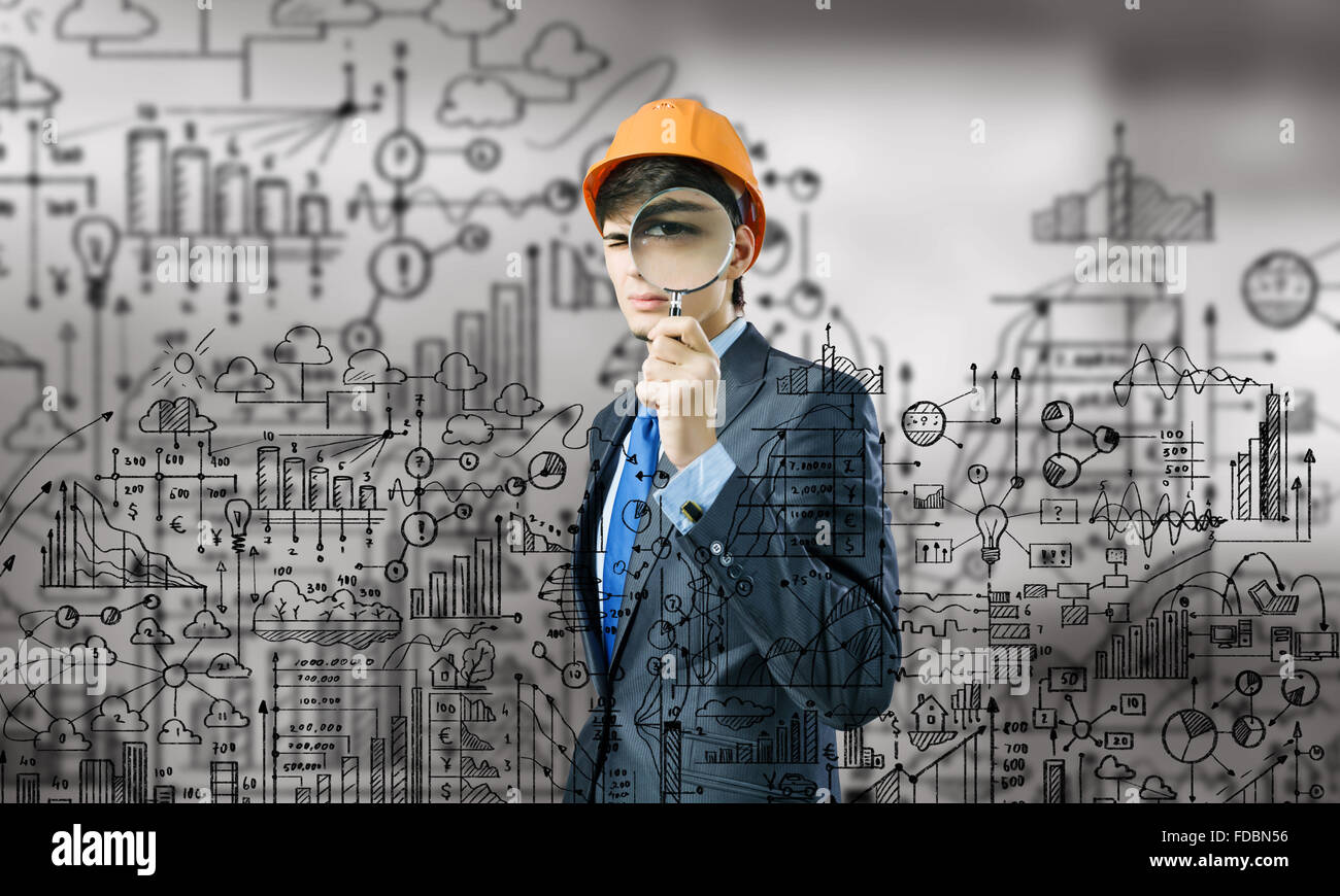 Young man architect against sketch background looking in magnifying ...
