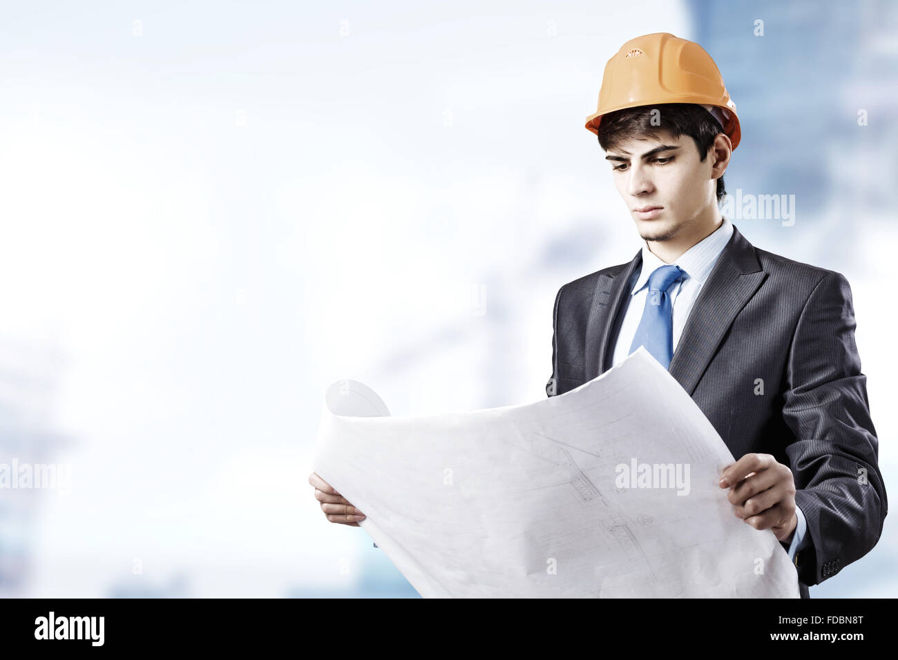 Young man architect looking at construction project Stock Photo - Alamy