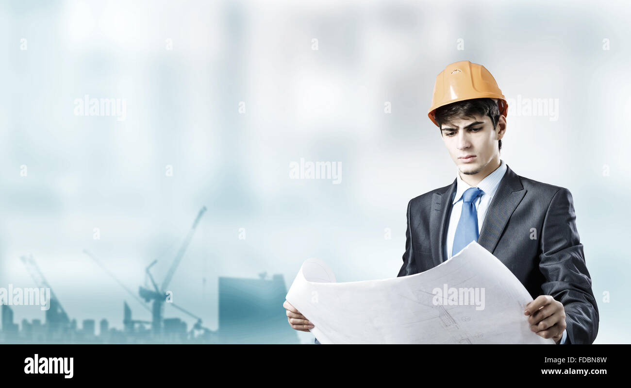 Young man architect looking at construction project Stock Photo - Alamy