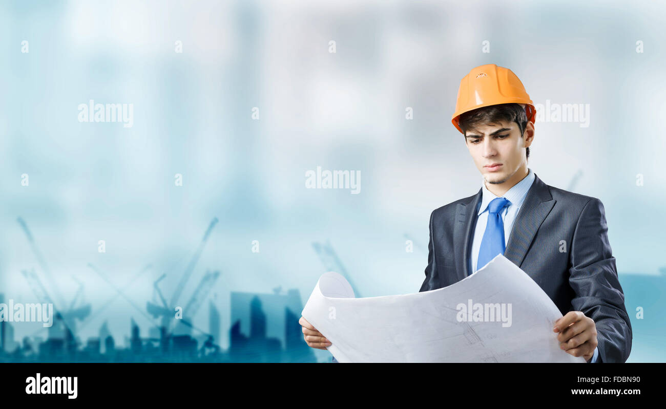 Young man architect looking at construction project Stock Photo - Alamy