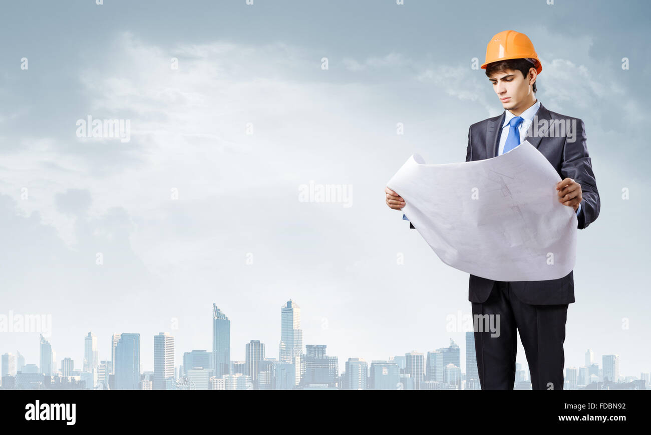 Young man architect looking at construction project Stock Photo - Alamy