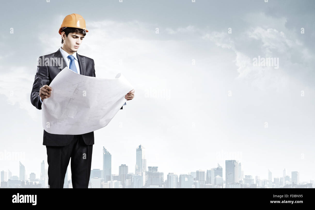 Young man architect looking at construction project Stock Photo - Alamy