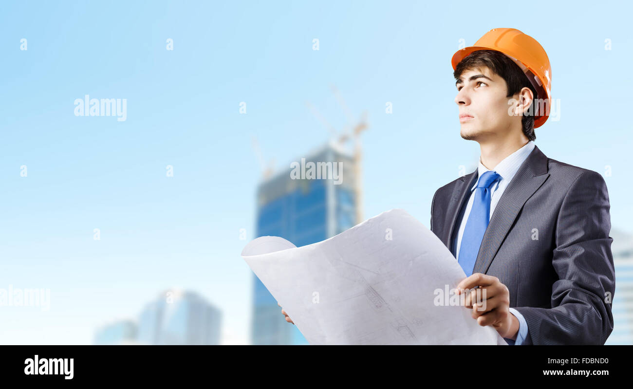 Young man architect looking at construction project Stock Photo - Alamy