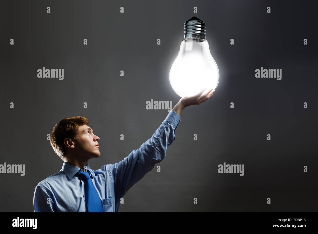 Young man holding light bulb in hand Stock Photo - Alamy