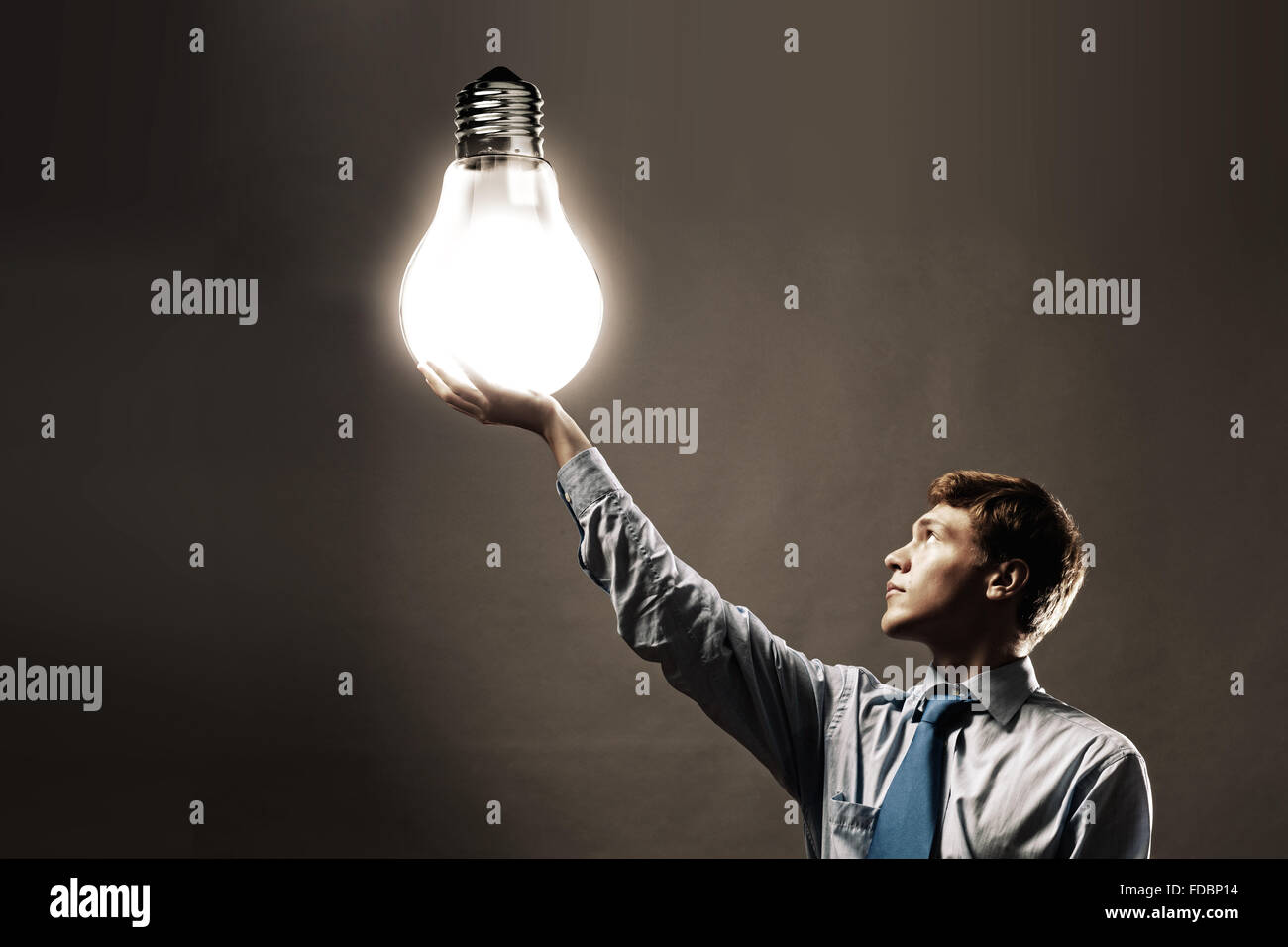 Young man holding light bulb in hand Stock Photo - Alamy
