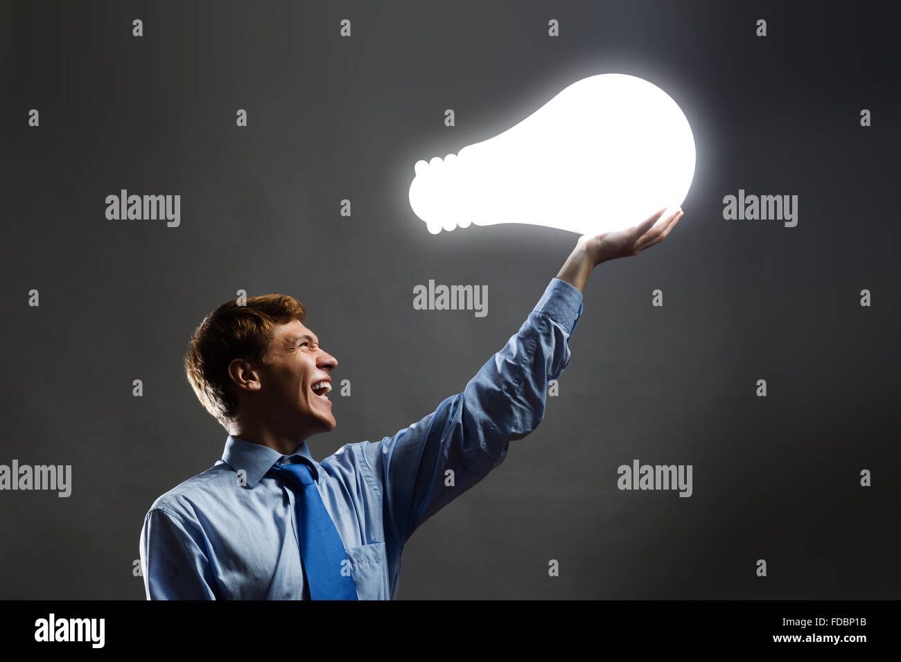 Young man holding light bulb in hand Stock Photo - Alamy