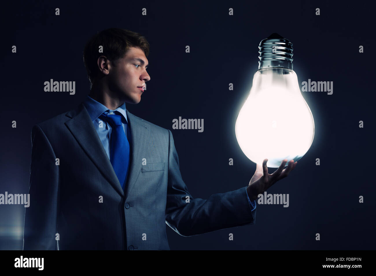 Young man holding light bulb in hand Stock Photo - Alamy