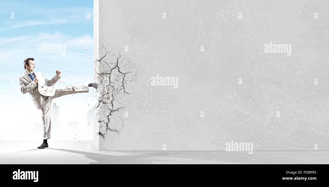 Businessman breaking stone wall with karate kick Stock Photo - Alamy