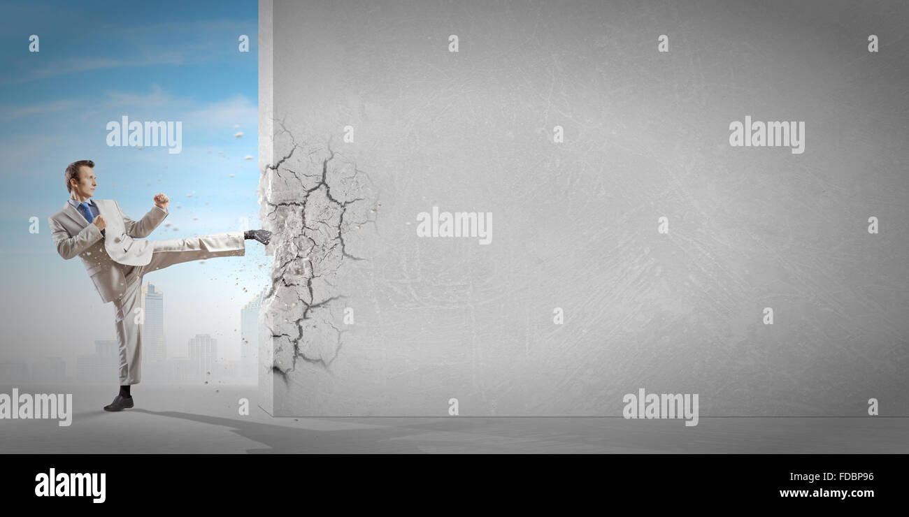 Businessman breaking stone wall with karate kick Stock Photo - Alamy