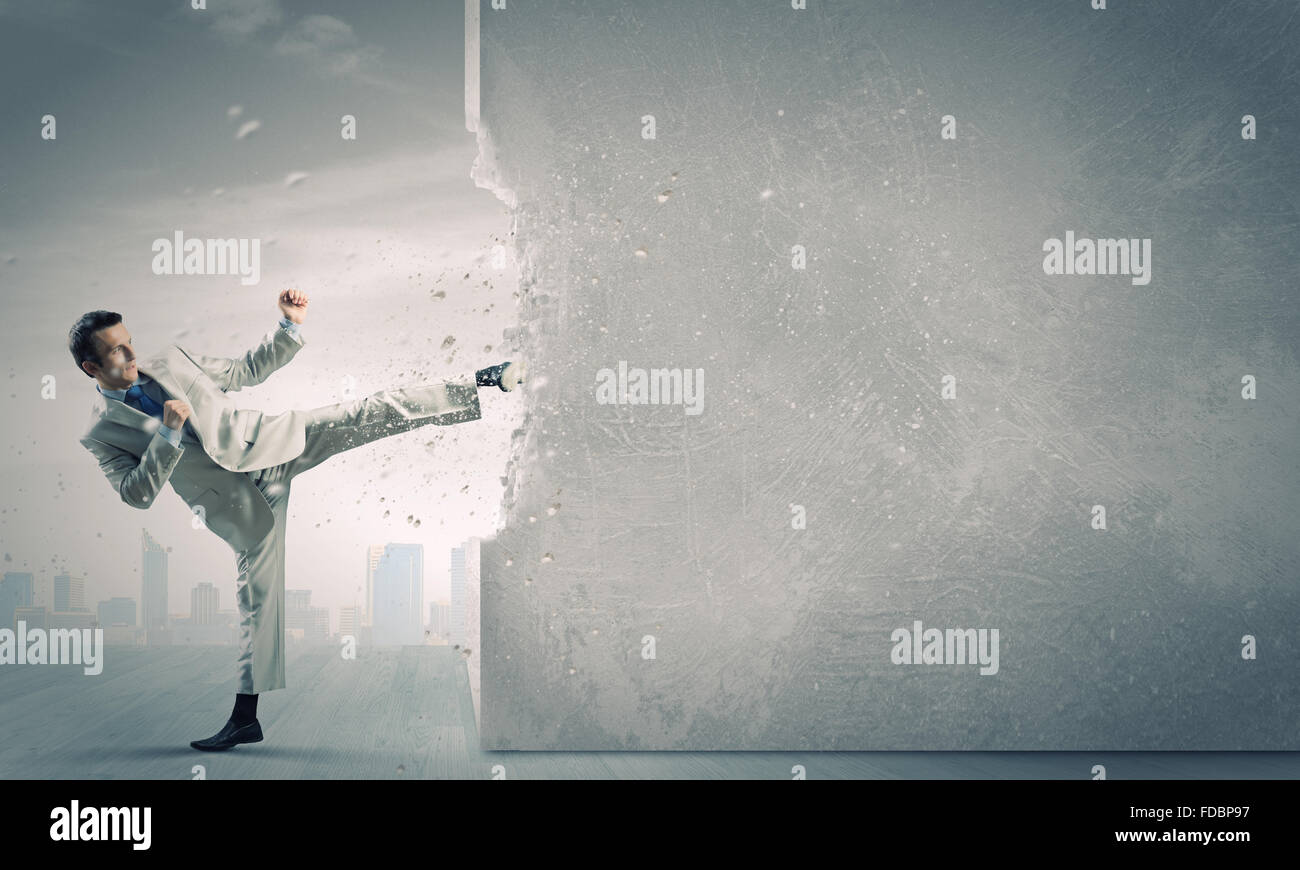 Businessman breaking stone wall with karate kick Stock Photo - Alamy