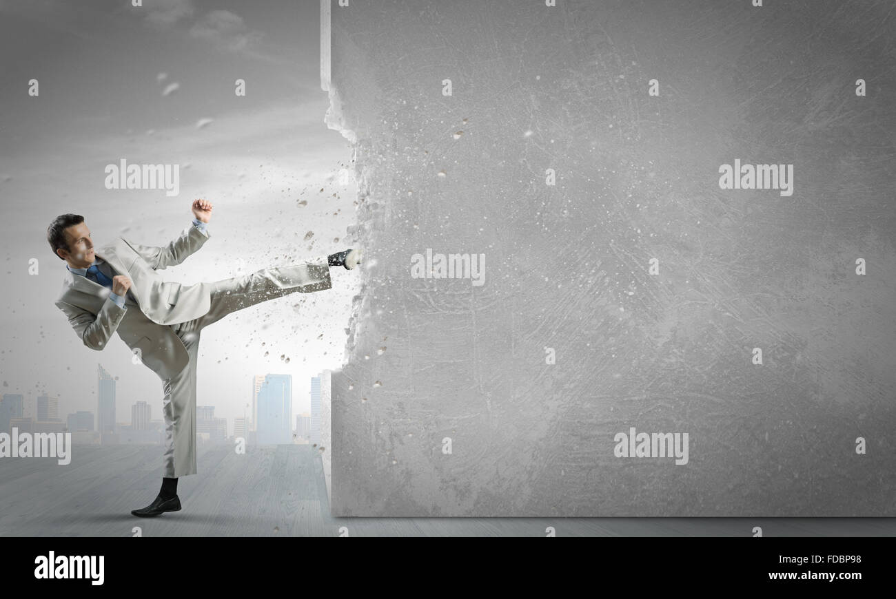 Businessman breaking stone wall with karate kick Stock Photo - Alamy