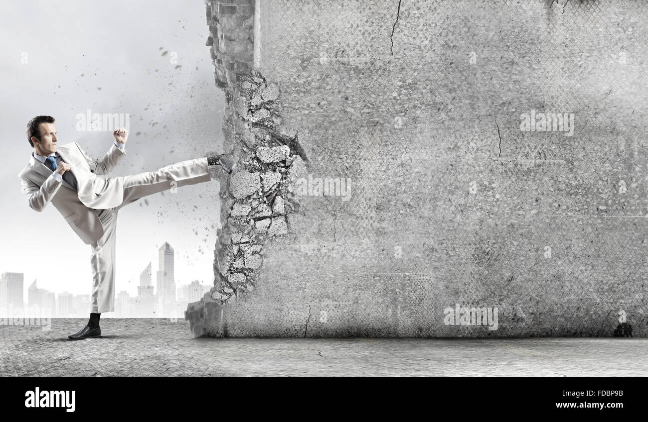 Businessman breaking stone wall with karate kick Stock Photo - Alamy