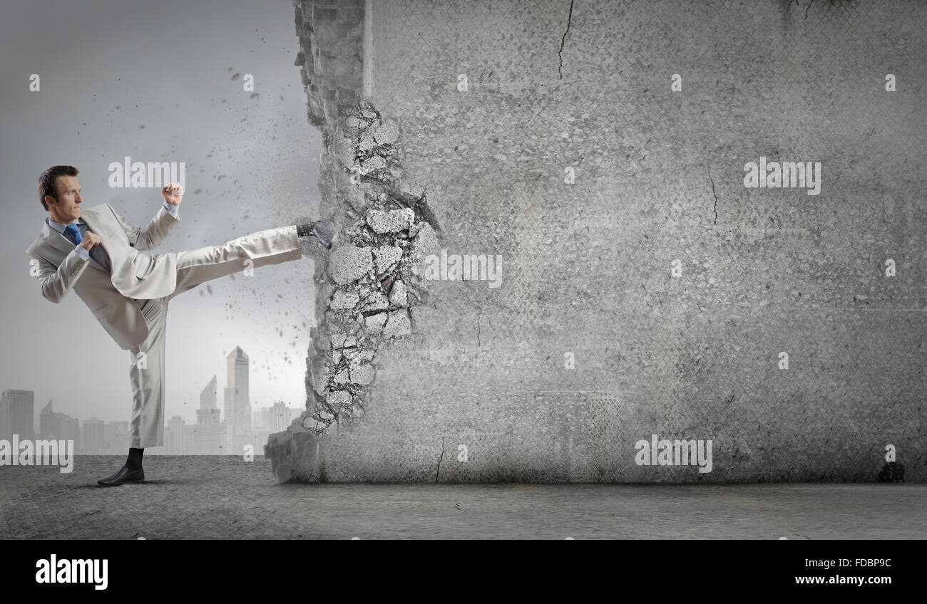 Businessman breaking stone wall with karate kick Stock Photo - Alamy