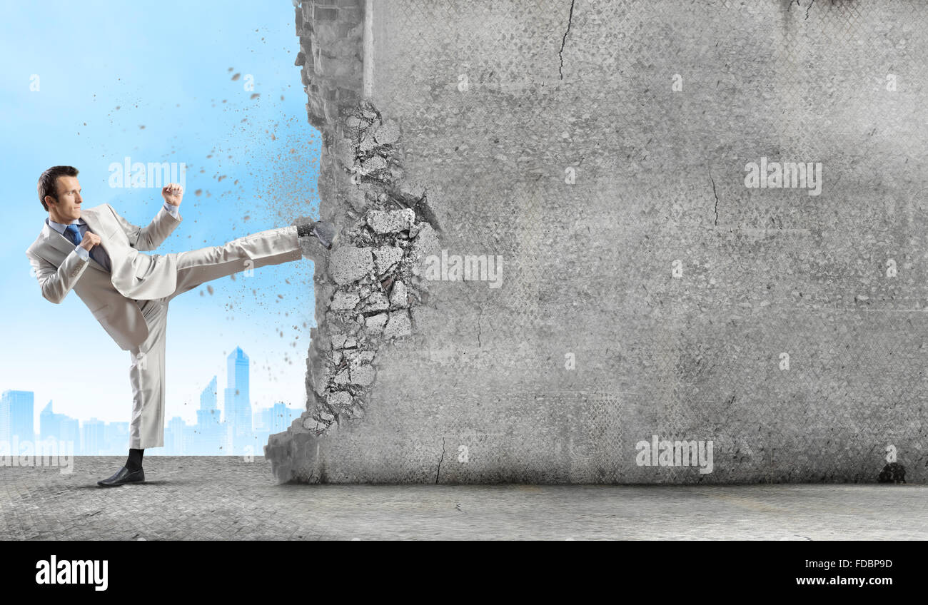 Businessman breaking stone wall with karate kick Stock Photo - Alamy