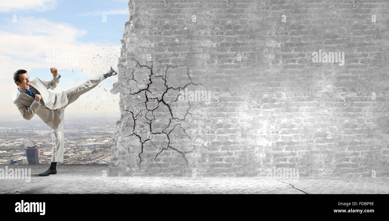 Businessman breaking stone wall with karate kick Stock Photo - Alamy