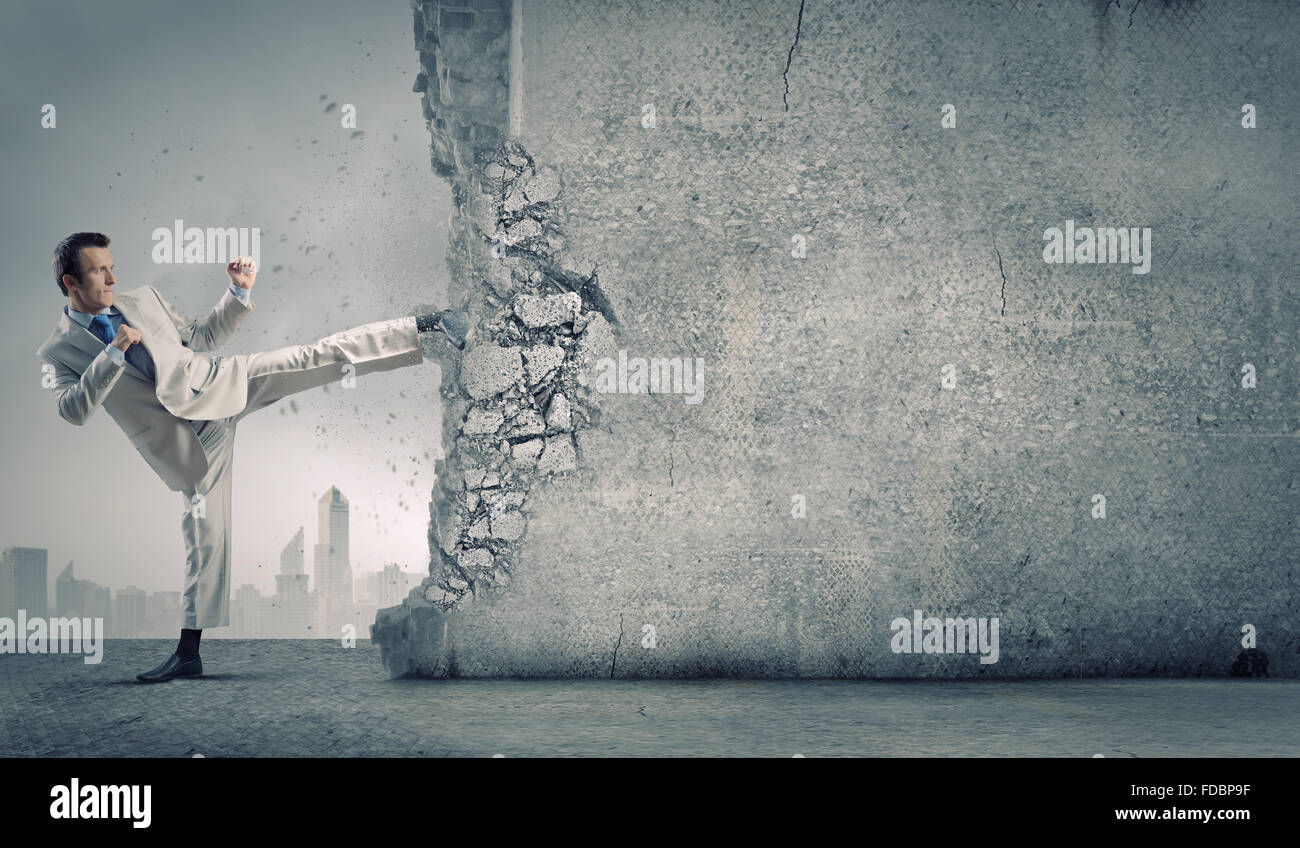 Businessman breaking stone wall with karate kick Stock Photo - Alamy