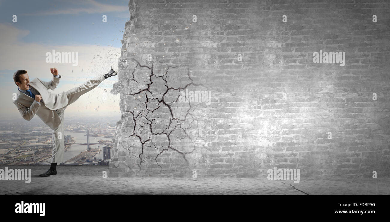 Businessman breaking stone wall with karate kick Stock Photo - Alamy