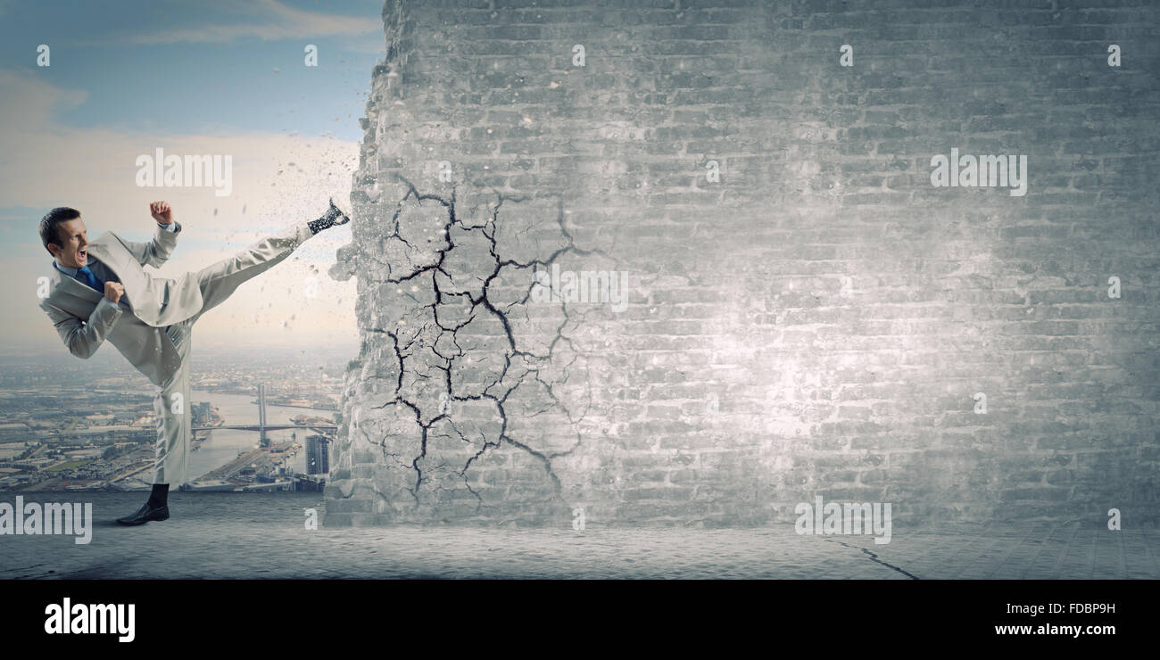 Businessman breaking stone wall with karate kick hi-res stock ...
