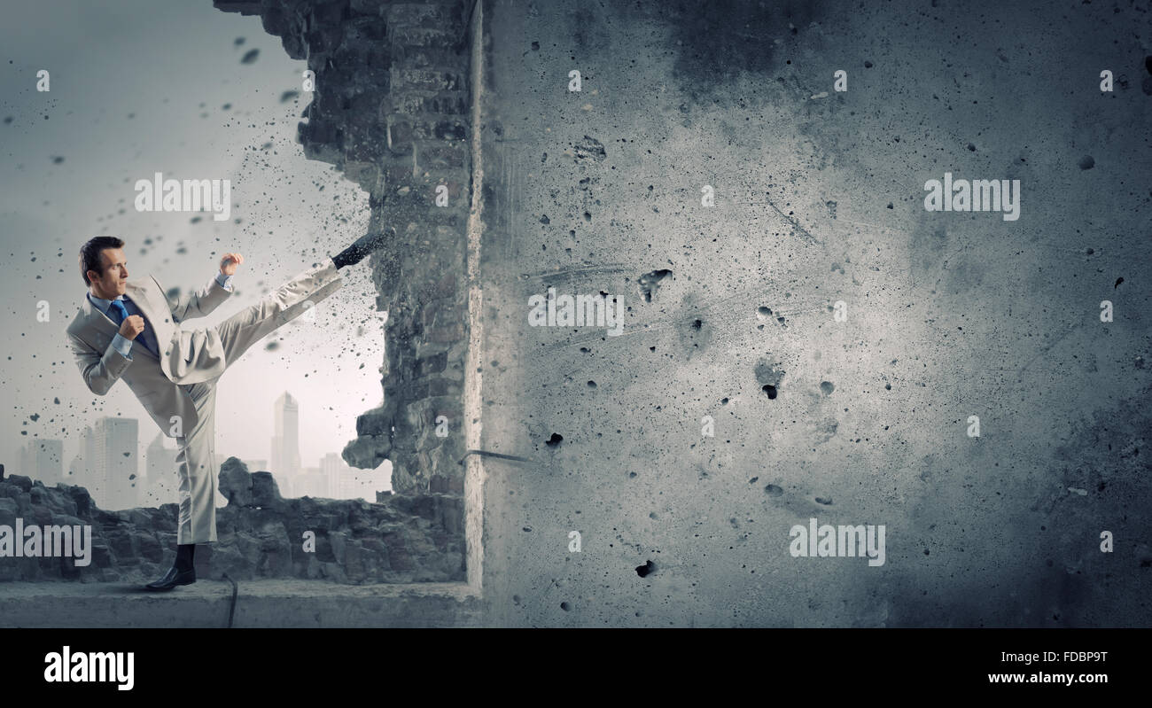 Businessman breaking stone wall with karate kick Stock Photo - Alamy
