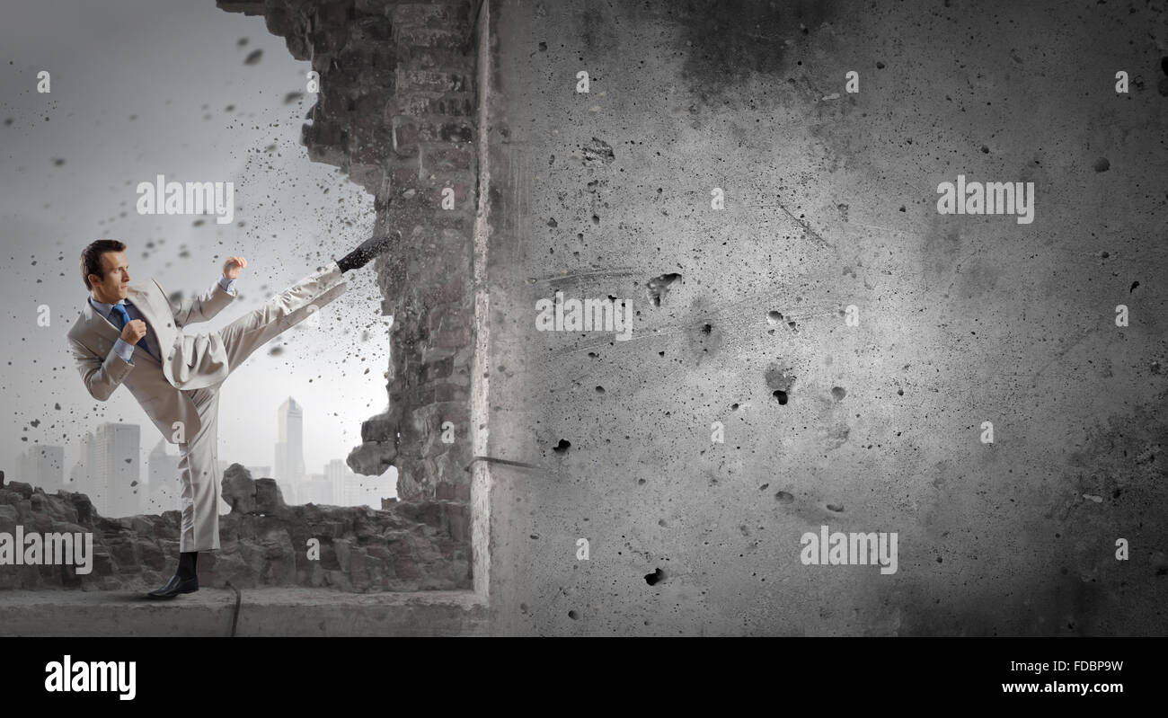 Businessman breaking stone wall with karate kick Stock Photo - Alamy