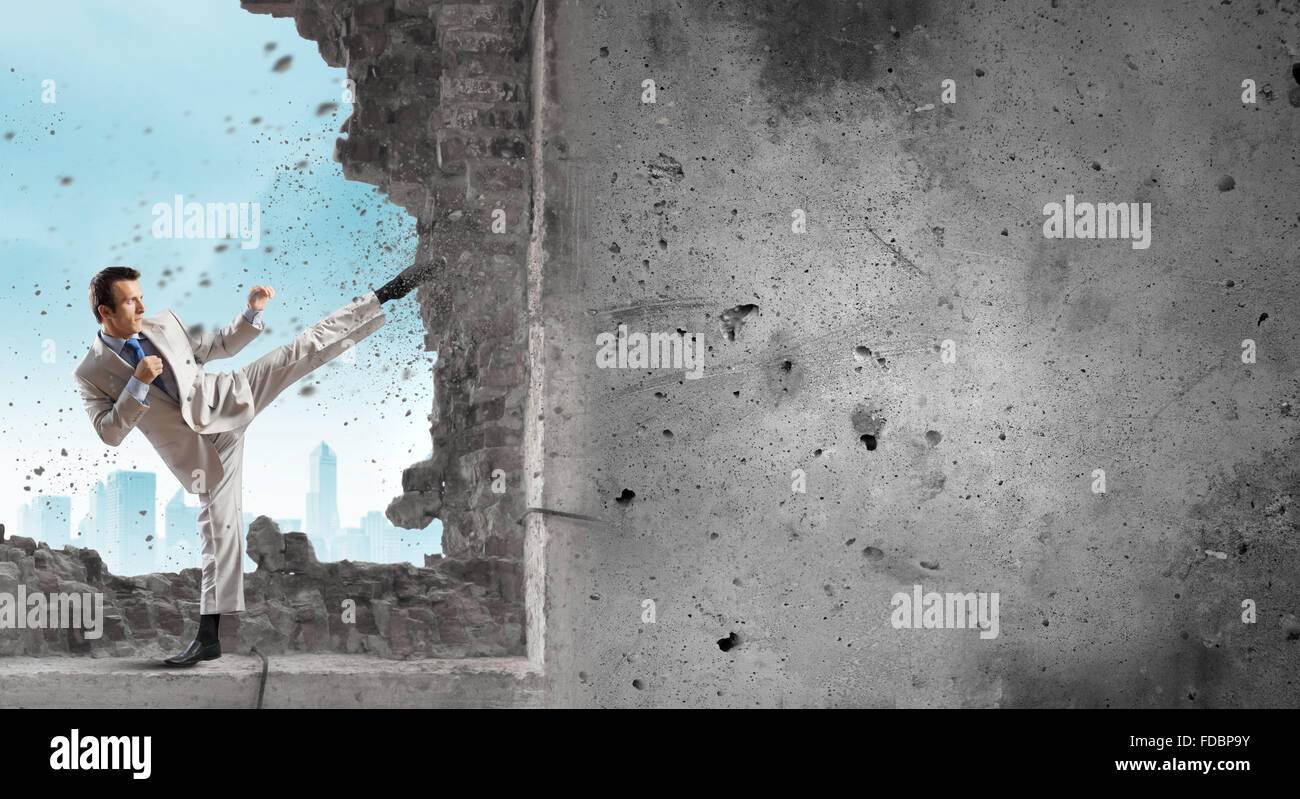 Businessman breaking stone wall with karate kick Stock Photo - Alamy
