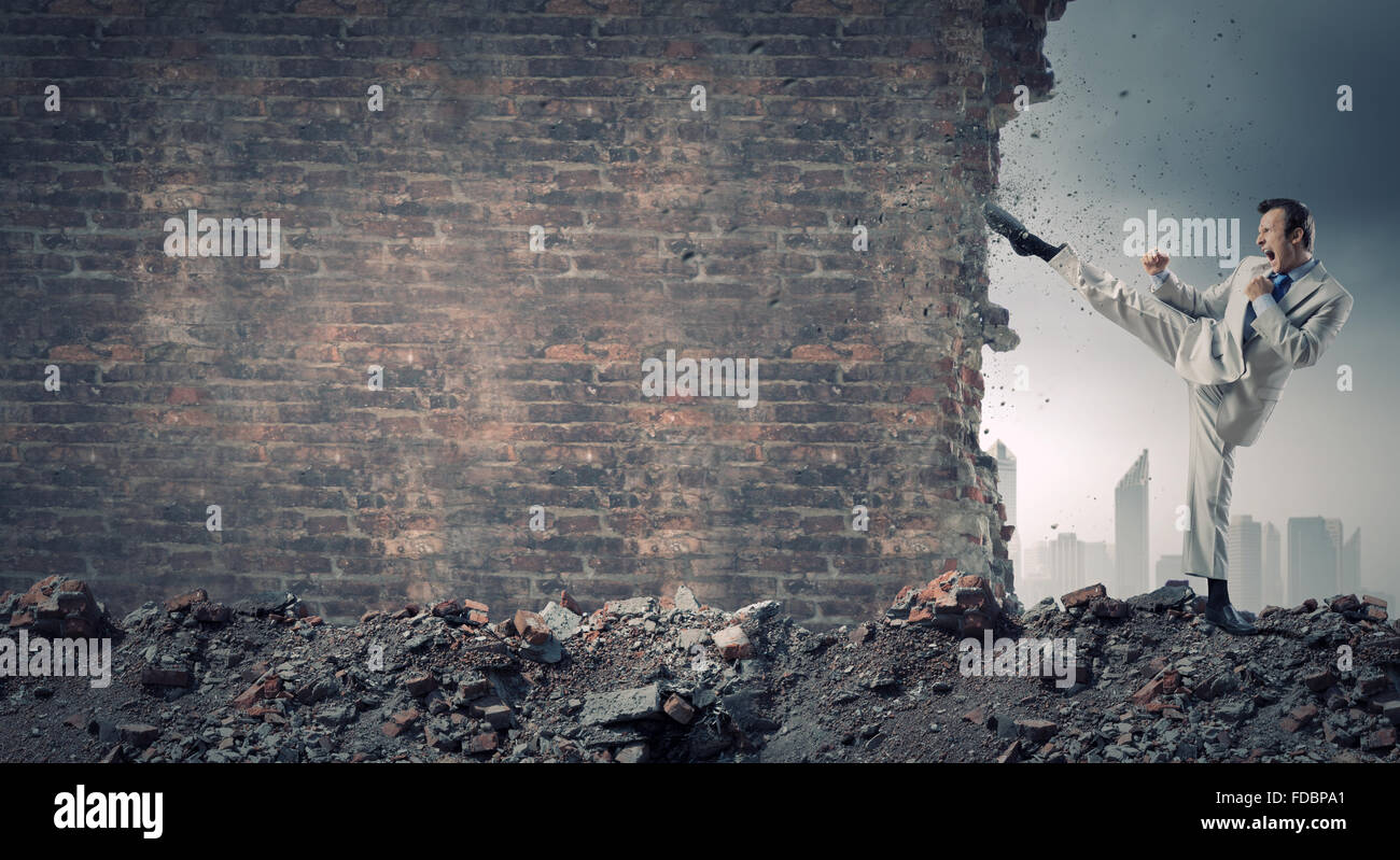 Businessman breaking stone wall with karate kick Stock Photo - Alamy