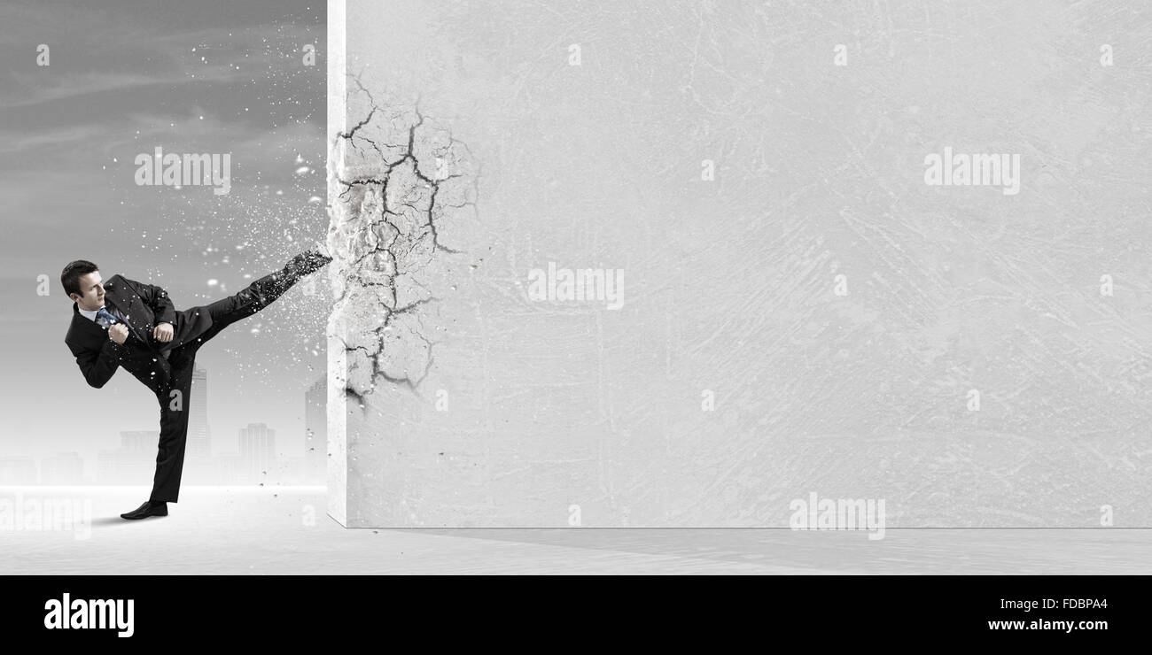 Businessman breaking stone wall with karate kick Stock Photo - Alamy