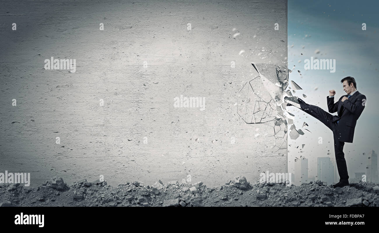 Businessman breaking stone wall with karate kick Stock Photo - Alamy