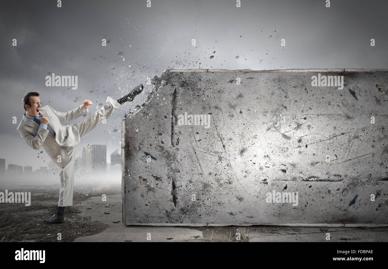 Businessman breaking stone wall with karate kick Stock Photo - Alamy