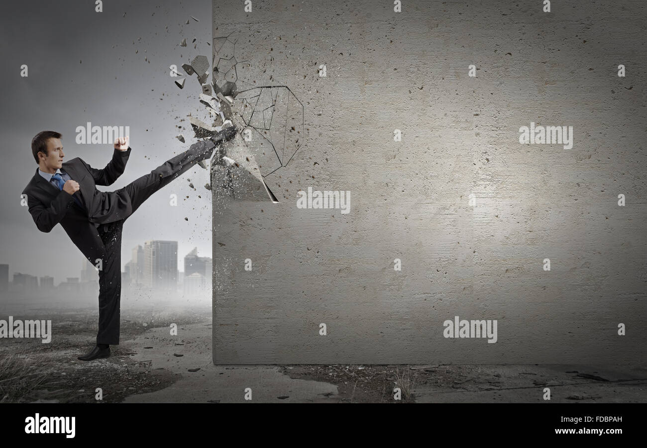 Businessman breaking stone wall with karate kick Stock Photo - Alamy