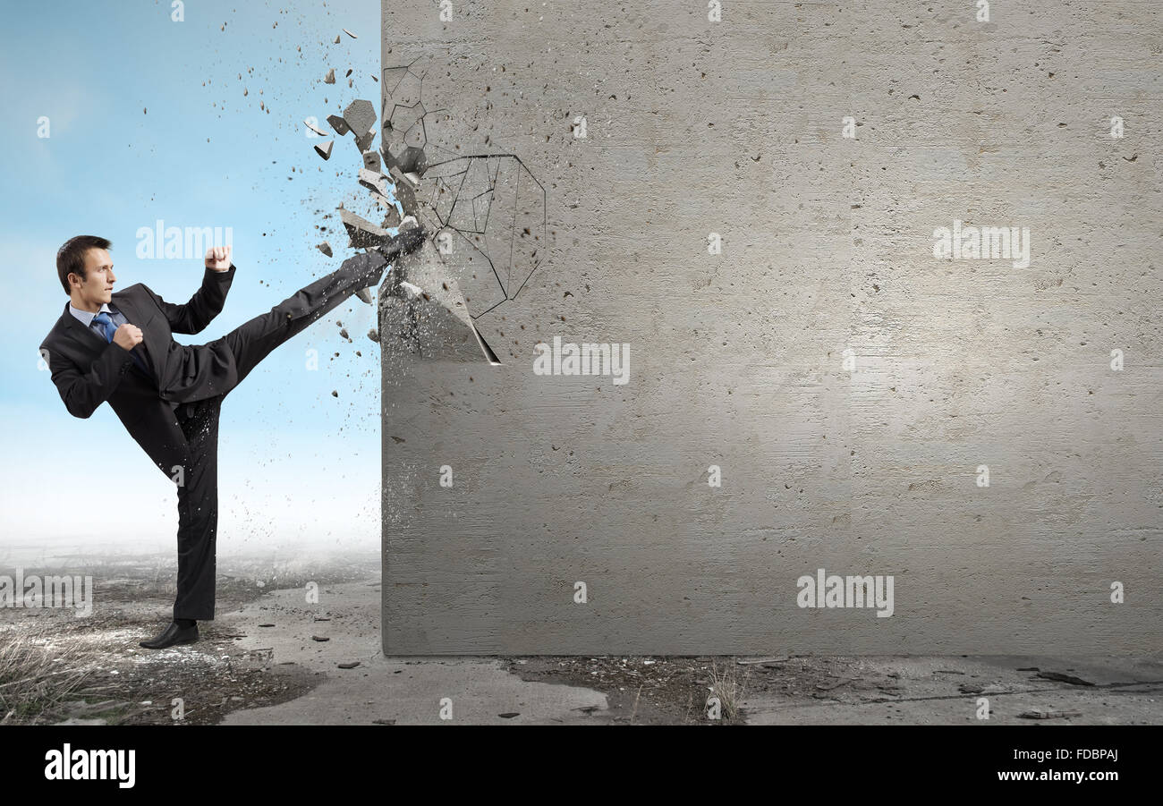 Businessman breaking stone wall with karate kick Stock Photo - Alamy