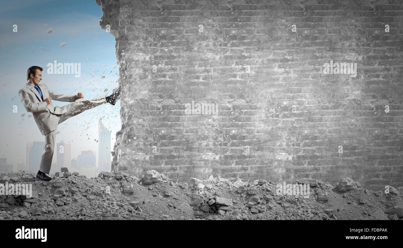 Businessman breaking stone wall with karate kick Stock Photo - Alamy