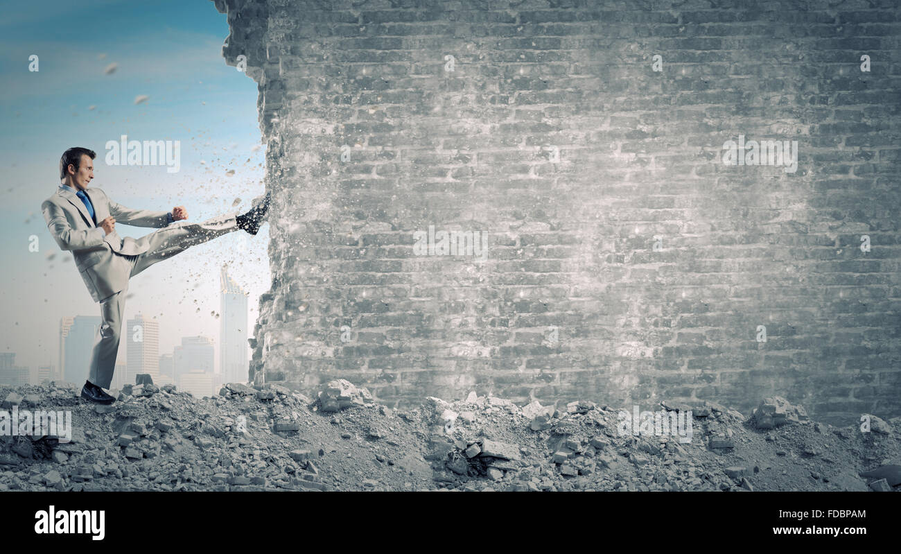 Businessman breaking stone wall with karate kick Stock Photo - Alamy