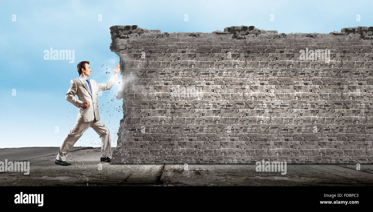 Businessman breaking stone wall with karate punch Stock Photo - Alamy