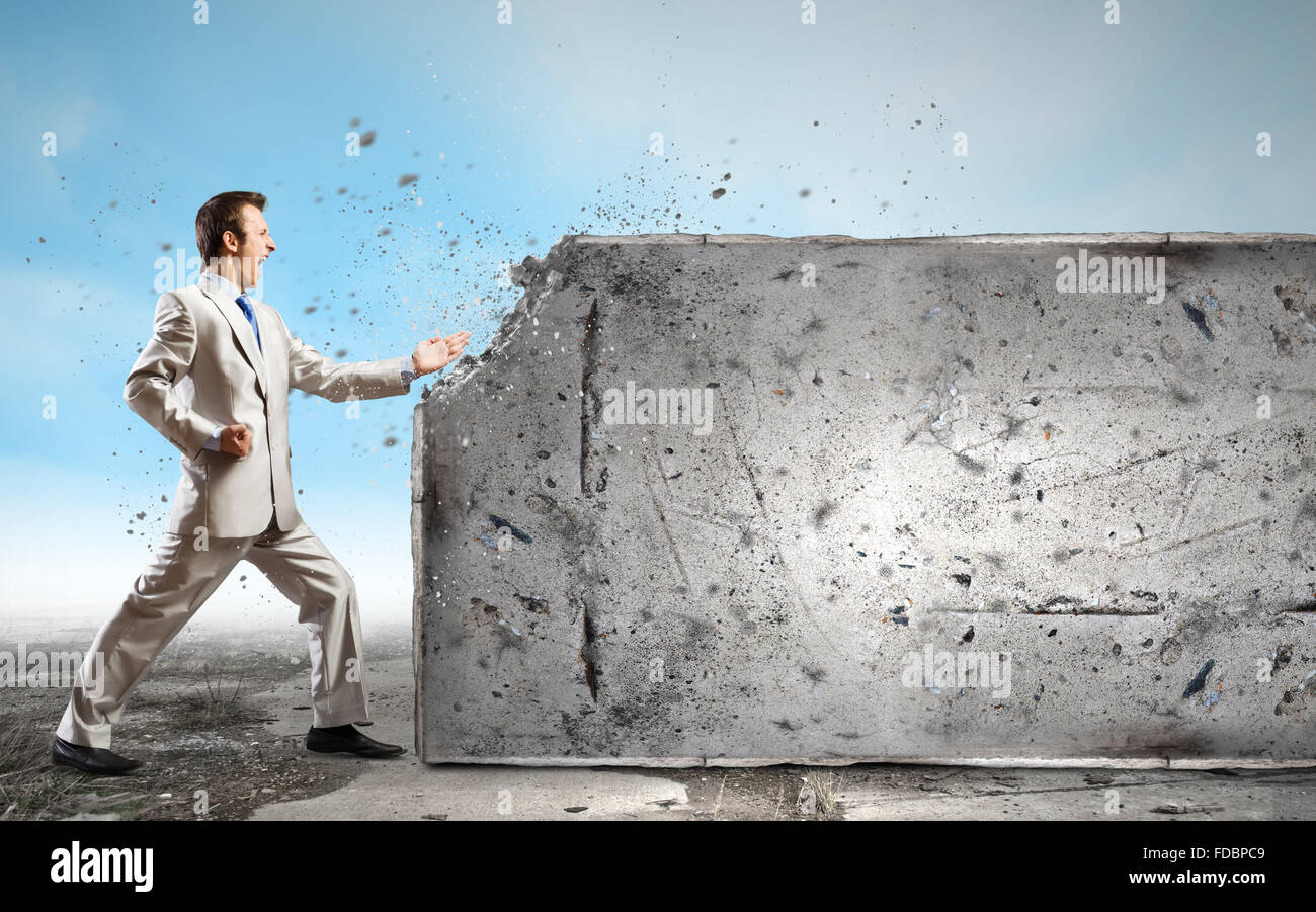 Businessman breaking stone wall with karate punch Stock Photo - Alamy