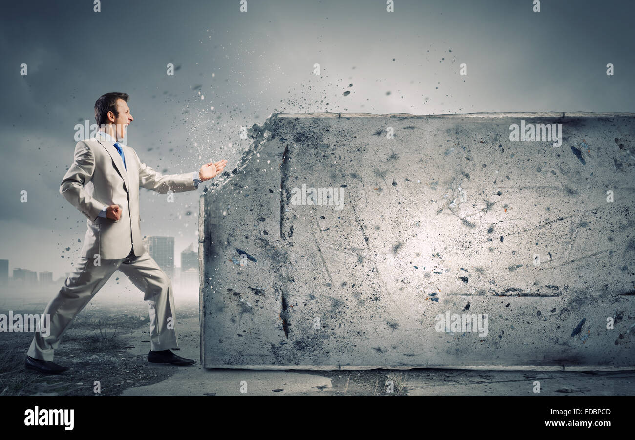 Businessman breaking stone wall with karate punch Stock Photo - Alamy