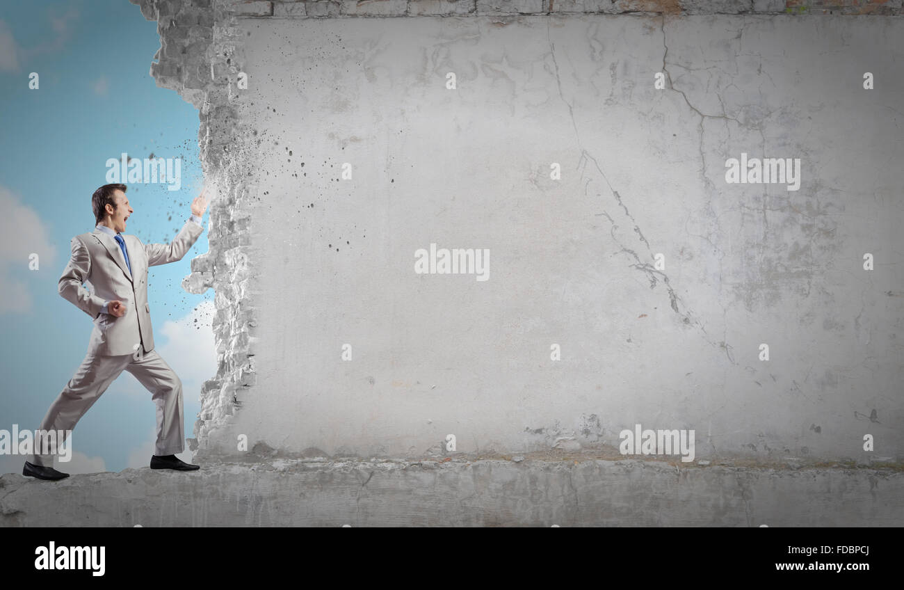 Businessman breaking stone wall with karate punch Stock Photo - Alamy