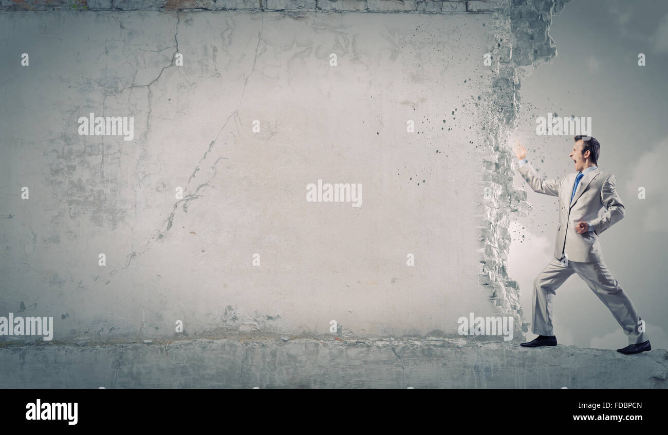 Businessman breaking stone wall with karate punch Stock Photo - Alamy