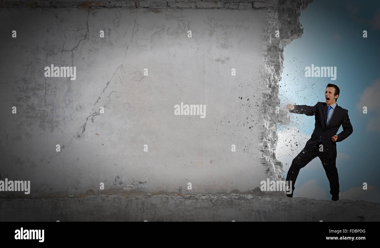 Businessman breaking stone wall with karate punch Stock Photo - Alamy