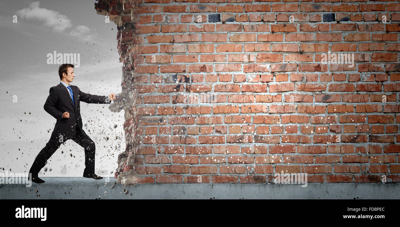 Businessman breaking stone wall with karate punch Stock Photo - Alamy