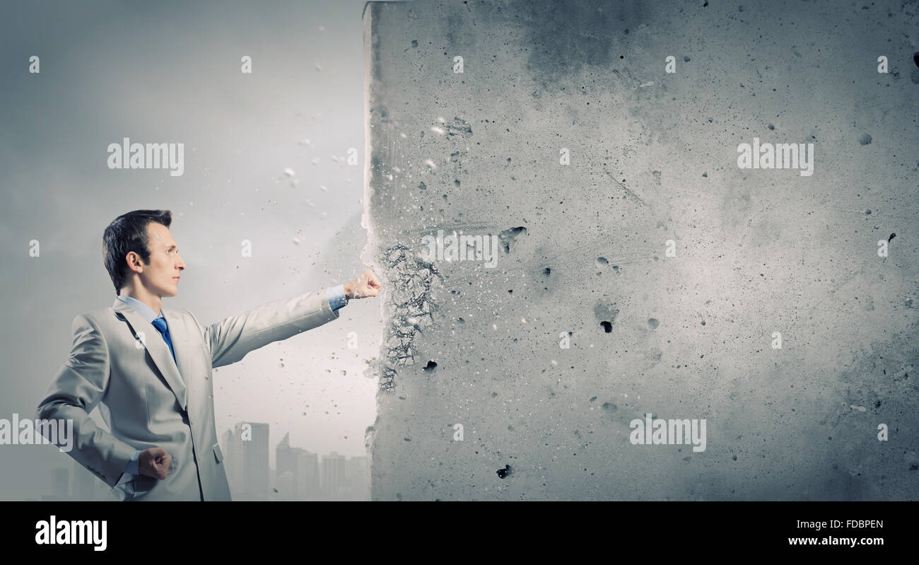 Businessman breaking stone wall with karate punch Stock Photo - Alamy