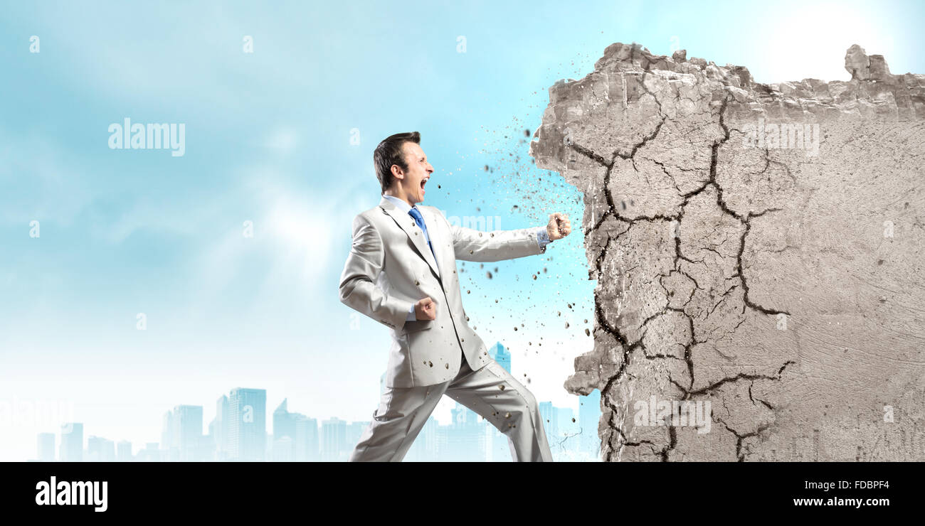 Businessman breaking stone wall with karate punch Stock Photo - Alamy