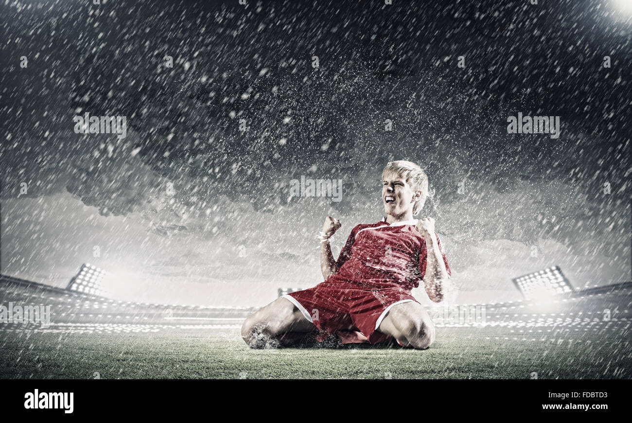Football player standing on knees and screaming with joy Stock Photo ...