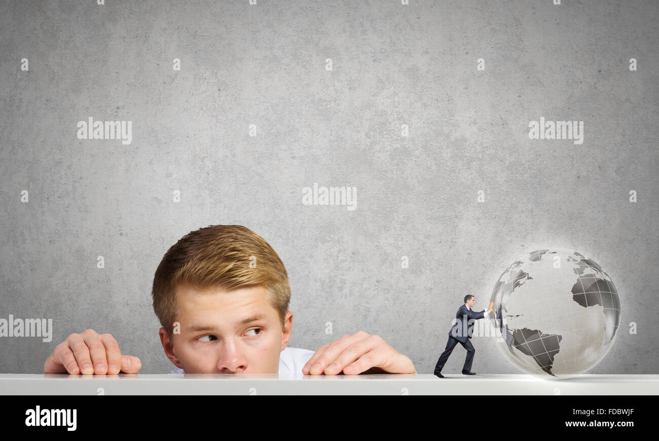 Young man looking out from under the table at businessman Stock Photo ...