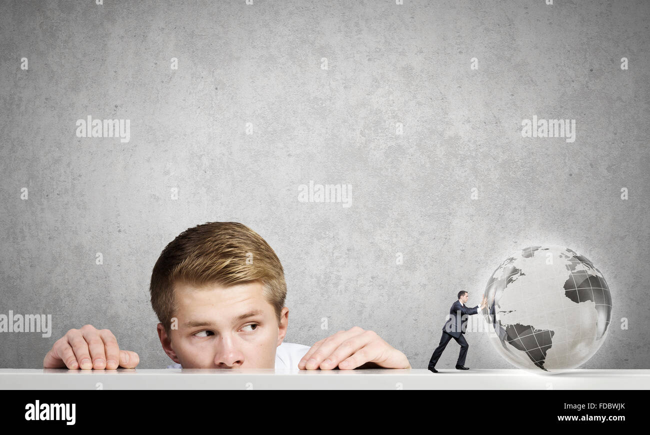 Young man looking out from under the table at businessman Stock Photo ...