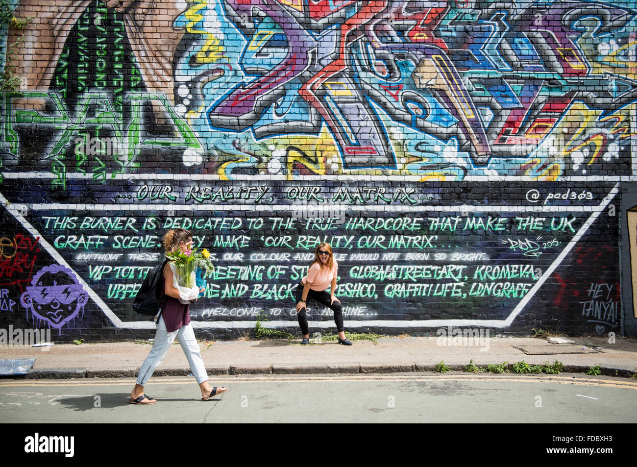 Girl is posing in front of the graffiti in Shoreditch while woman ...