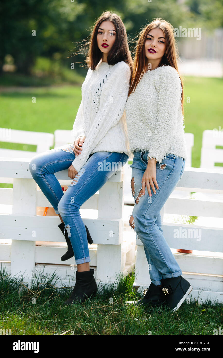 Two girls lean on a white bench in the park Stock Photo - Alamy